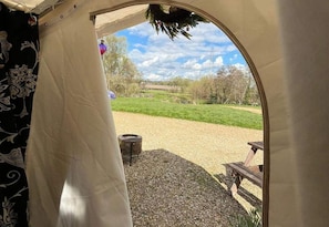 Uma tenda com vista para um campo gramado e uma mesa de piquenique.