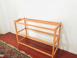 Prateleira de madeira contra uma parede branca e chão vermelho.
