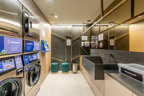 Casa de banho moderna com espaço para lavandaria autónoma, incluindo máquinas de lavar e secar roupa, e lavatório com espelho.