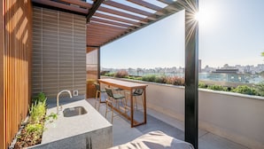 Terraço no telhado com pérgola de madeira, pia embutida e mesa com cadeiras.