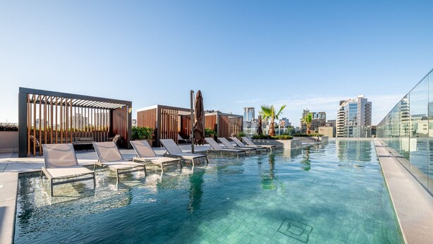 Uma área de piscina no terraço, com espreguiçadeiras e uma estrutura de edifício moderna.