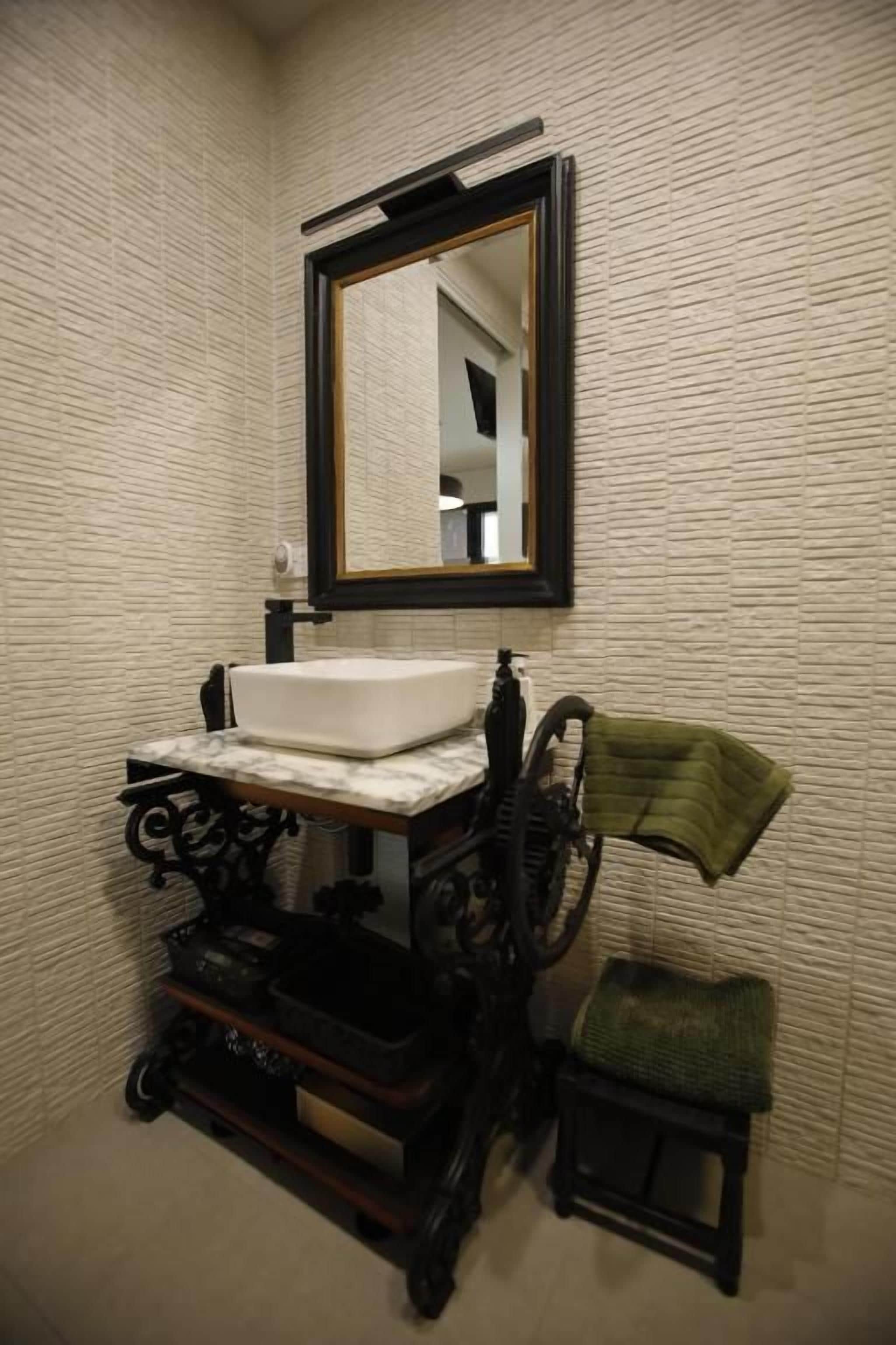 Casa de banho com lavatório branco, espelho e suporte para toalhas.