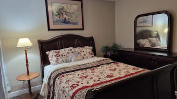 Quarto com cama, abajur, cômoda, espelho e quadro na parede.