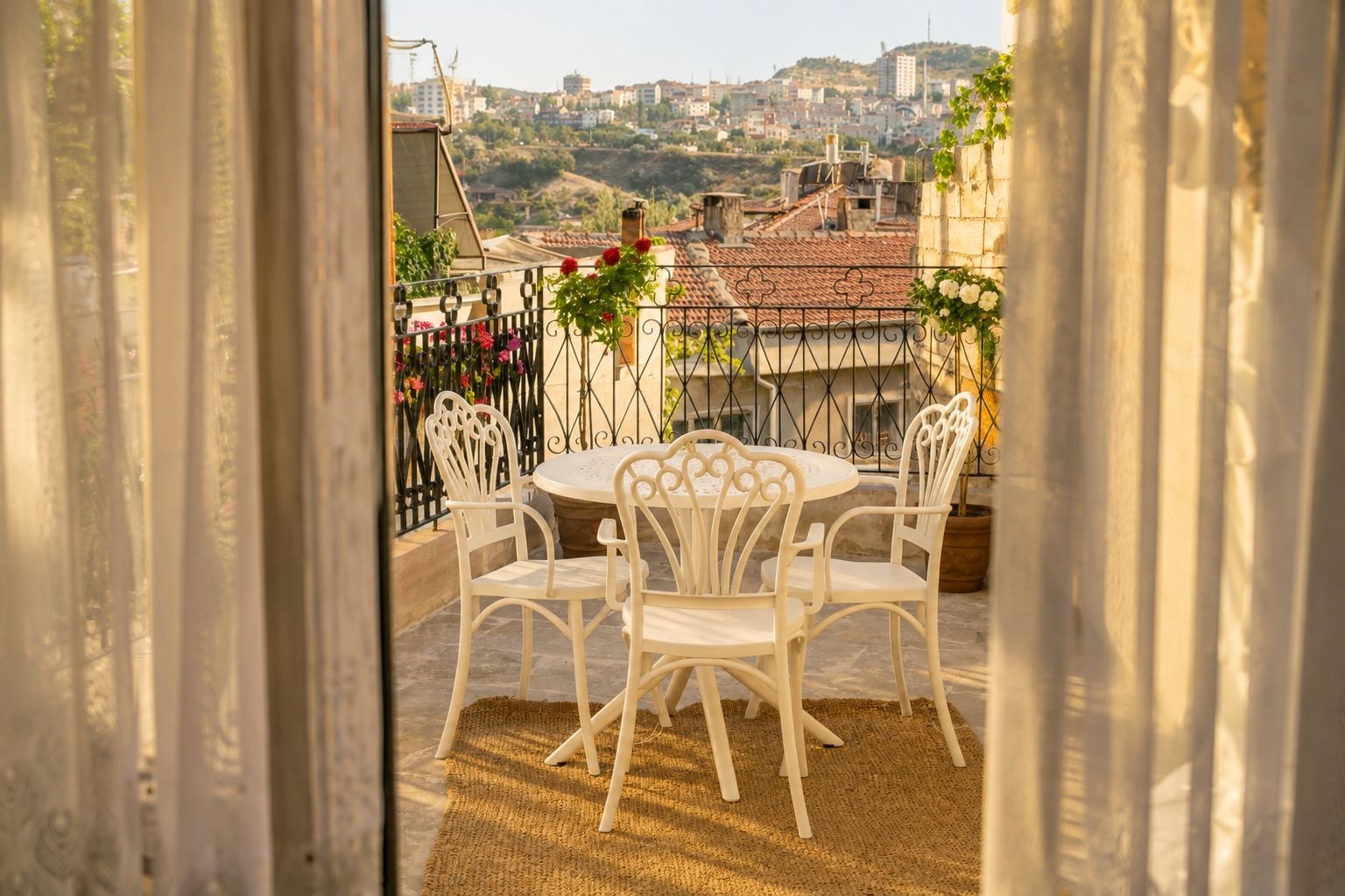 Um terraço com mesa redonda e cadeiras, vista para o horizonte urbano e um cercado decorativo.