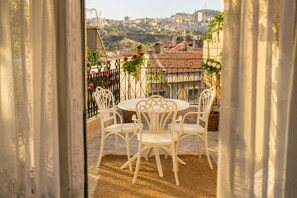 Um terraço com mesa redonda e cadeiras, vista para o horizonte urbano e um cercado decorativo.