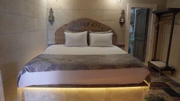 Uma cama com cabeceira identificada como 'ANGELS CITY', uma mesinha de cabeceira e um criado-mudo.