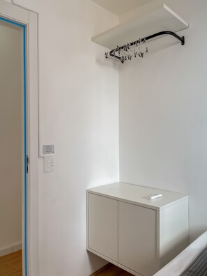 Quarto com armário branco, porta com detalhe azul e suporte no teto.