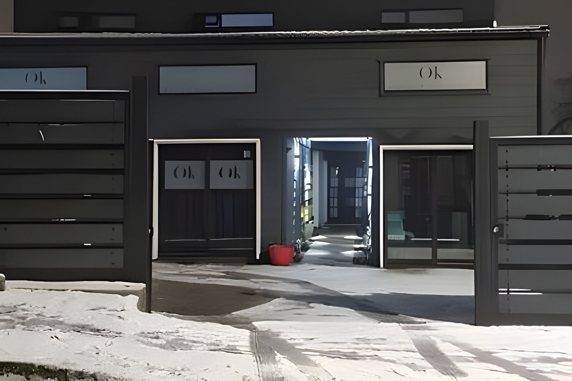 Entrada de prédio com duas portas identificadas com 'OK' e um caminho que leva para dentro.