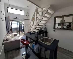 Um espaço de estar moderno com escada, área de jantar e sofá.