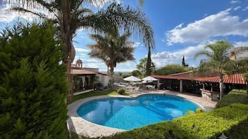 Piscina rodeada por vegetação exuberante e um céu azul límpido.