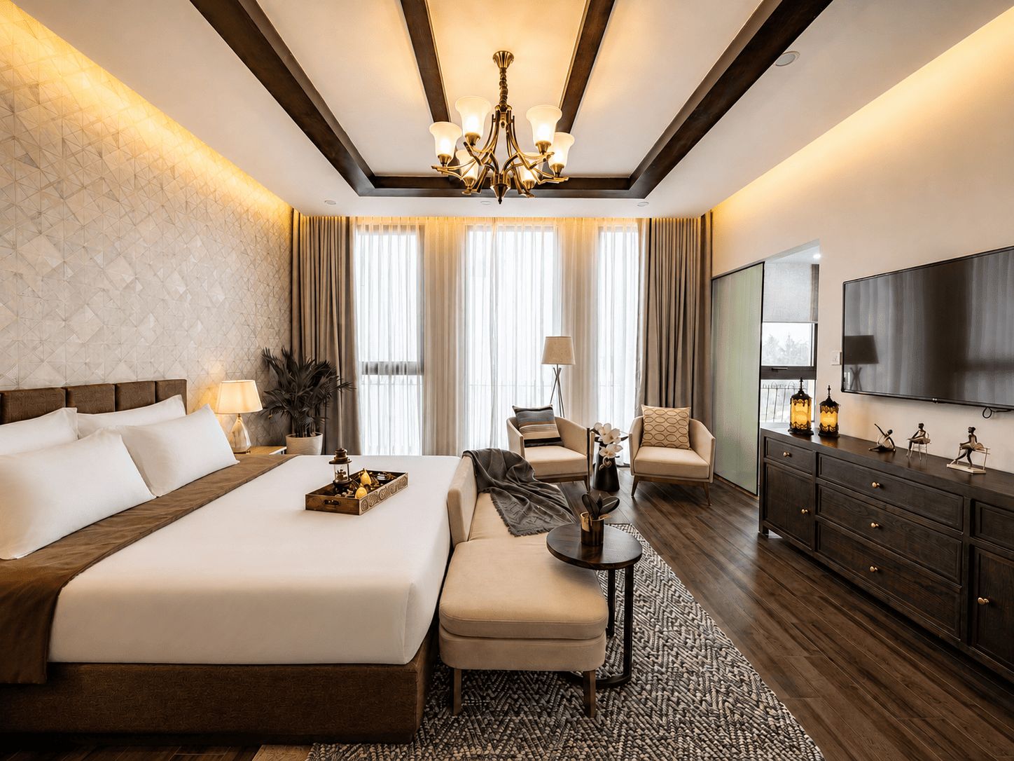 Quarto de hotel com cama grande, sofá, televisão e lustre.