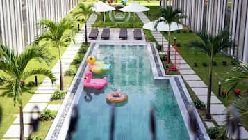 Piscina com espreguiçadeiras e brinquedos infláveis.