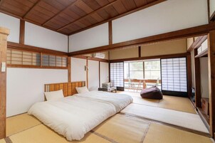 Um quarto em estilo japonês tradicional, com tatames, cama de madeira e portas deslizantes.
