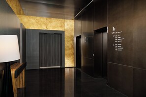 Interior moderno de elevador com visor digital exibindo números e nomes de quartos.