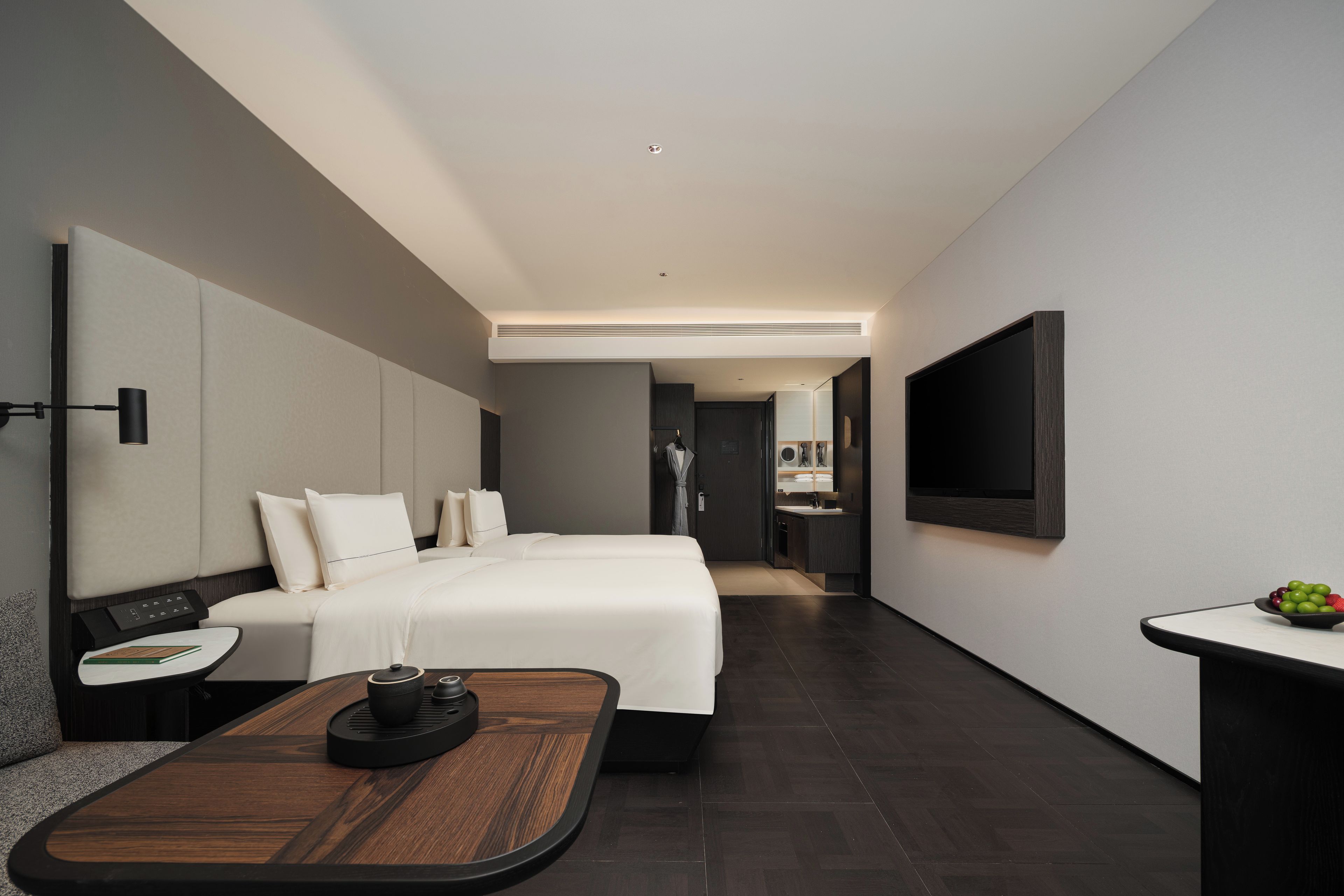 Quarto de hotel moderno com uma cama, mesa de cabeceira e televisão fixada na parede.