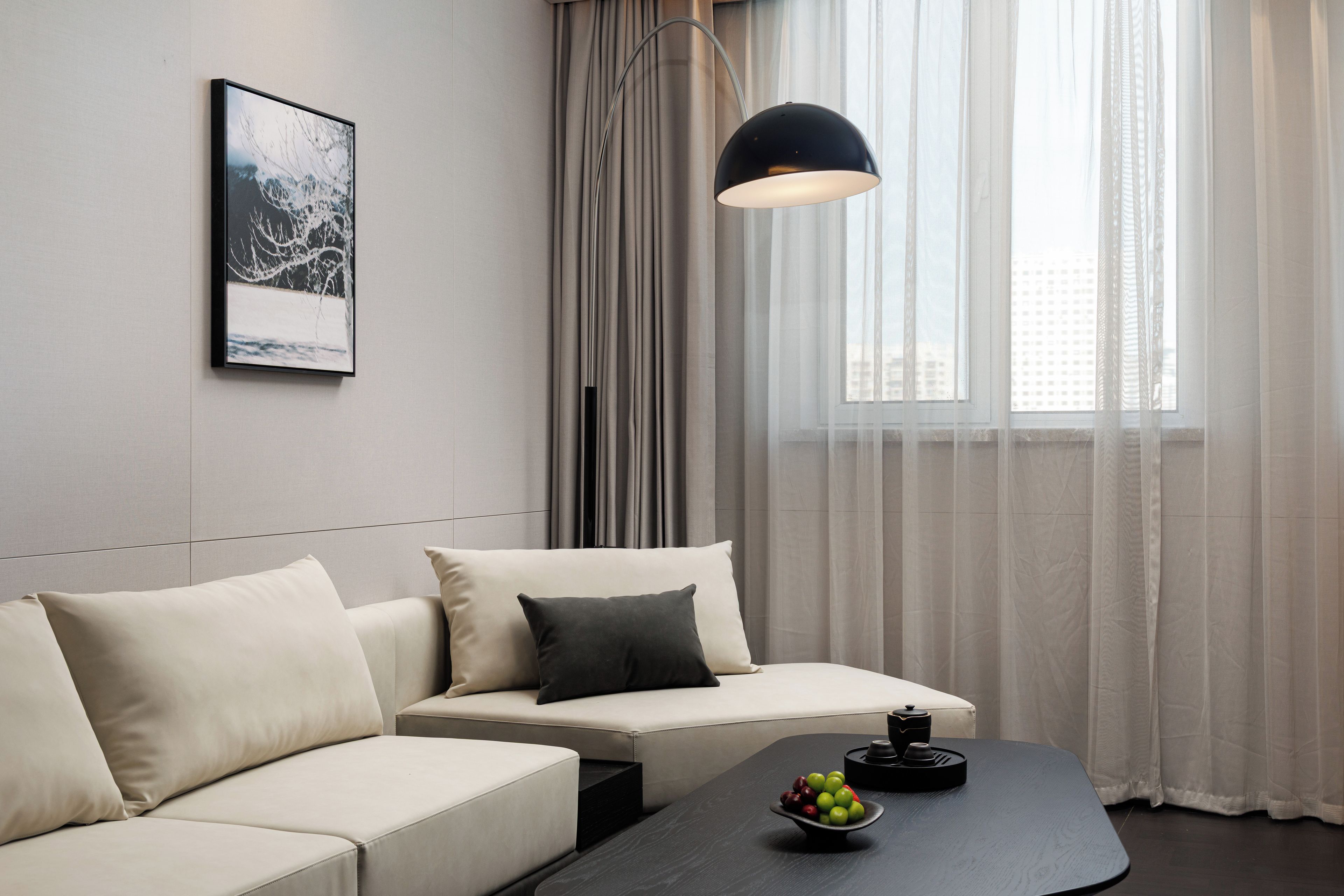 Uma sala de estar moderna com um sofá, uma mesa de centro com frutas e uma luminária pendente.