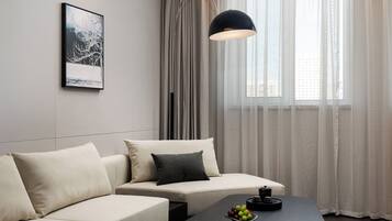 Uma sala de estar moderna com um sofá, uma mesa de centro com frutas e uma luminária pendente.
