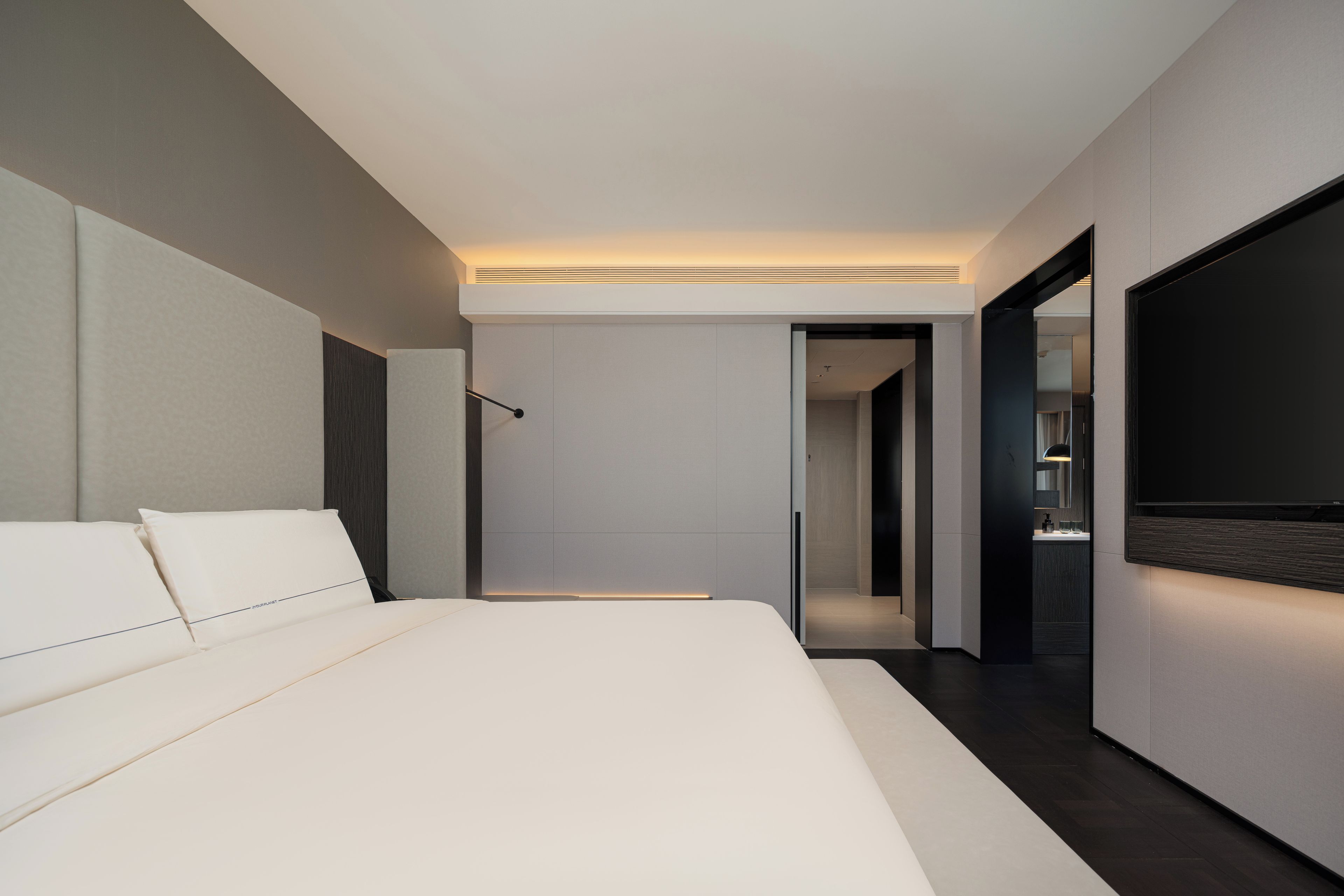 Quarto de hotel moderno com uma cama grande, televisão de tela plana e closet espaçoso.