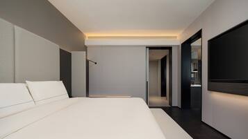 Quarto de hotel moderno com uma cama grande, televisão de tela plana e closet espaçoso.