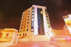 Edifício moderno com várias andares, design arquitetônico marcante, fachada em vidro e uma série de varandas.