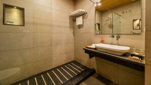 Casa de banho moderna com chuveiro, lavatório e espelho.