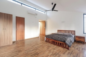 Quarto espaçoso com cama de madeira, ventoinha no teto e uma janela grande.