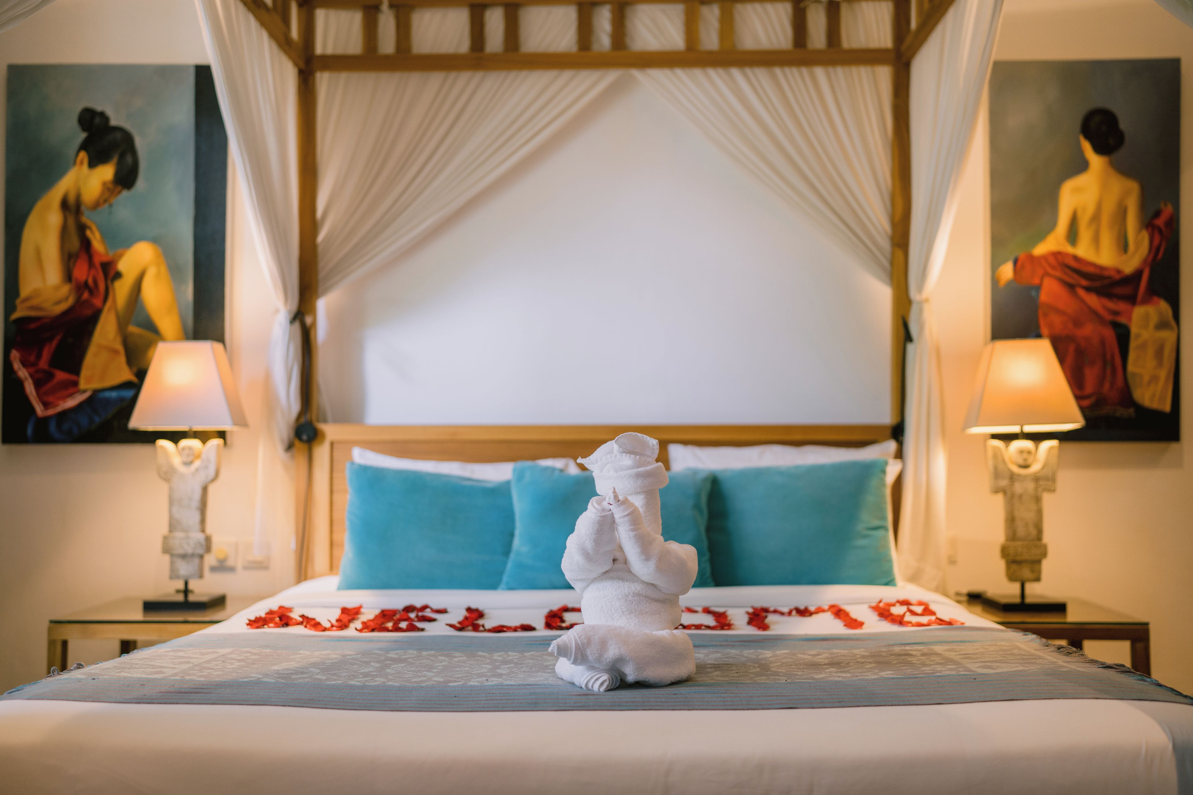 Quarto de hotel com cama, mesa de cabeceira, luminária e um quadro na parede.