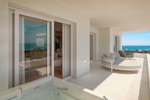 Interior moderno com porta de vidro que dá para uma varanda com vista para o mar.