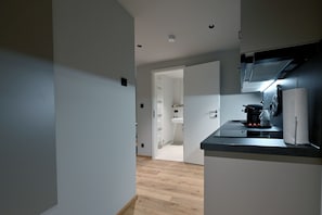 Cozinha moderna com bancada preta, máquina de café e dispensador de papel toalha.