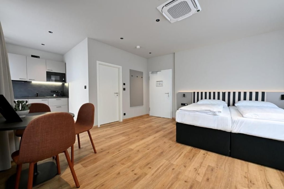 Quarto de hotel moderno com cama, escrivaninha e espaço para refeições.