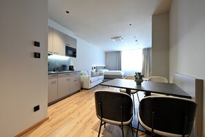 Uma cozinha moderna com eletrodomésticos embutidos, uma sala de jantar com mesa e cadeiras, e uma sala de estar com sofá e cama.