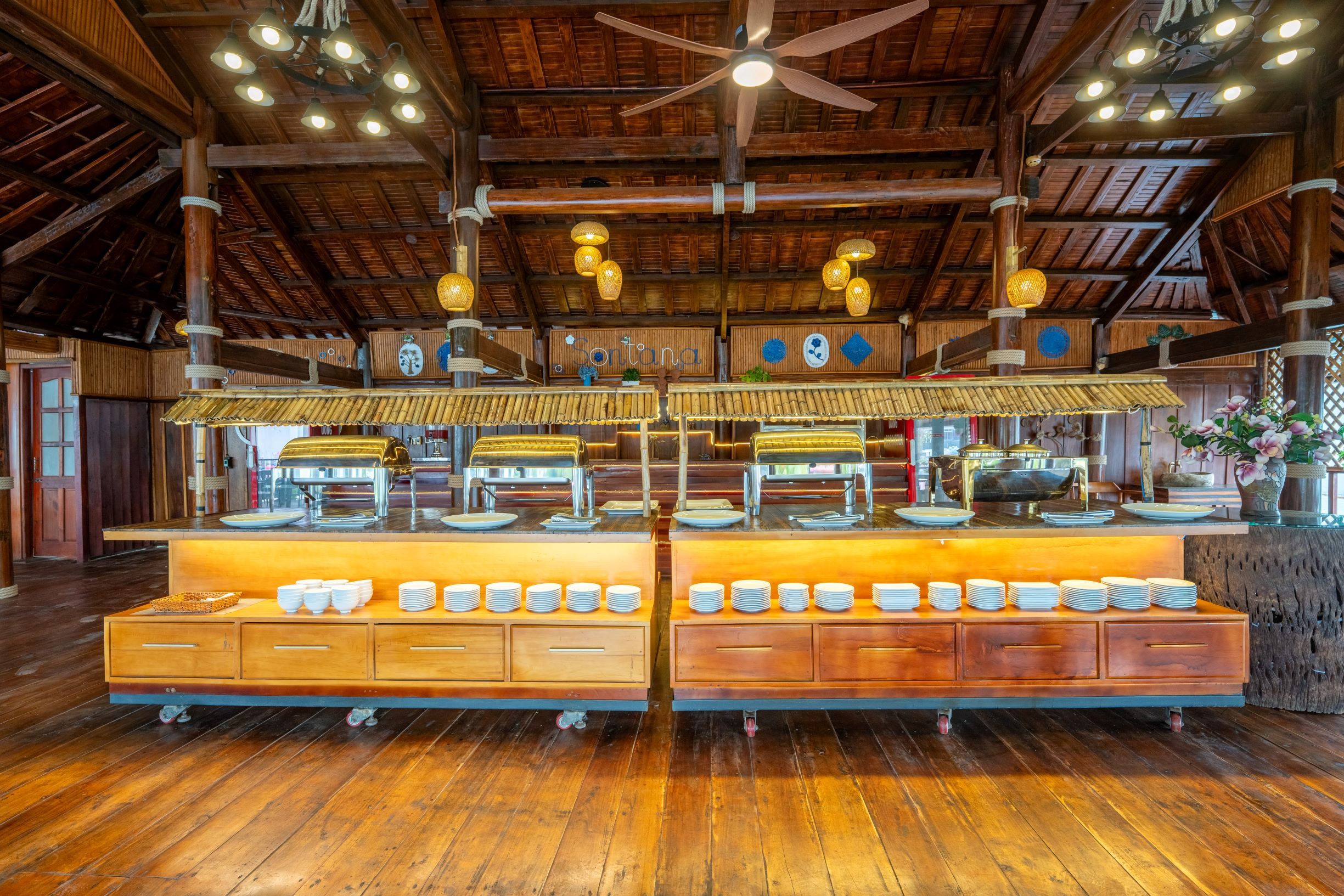 Disposição de buffet com várias estações de serviço, um ventilador de teto e vigas de madeira.