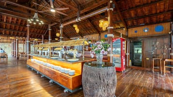 Amplo espaço interno com teto de madeira e mesa de buffet.