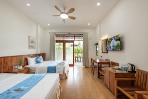 Quarto de hotel com duas camas, uma escrivaninha, uma cadeira, uma televisão e um ventilador de teto.