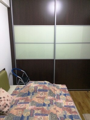 Quarto com cama, cadeira e piso de madeira.