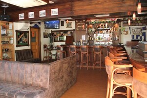 Um bar com decoração em madeira, banquetas e balcão.