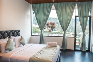 Quarto de hotel com cama, cortinas e vista para a paisagem.