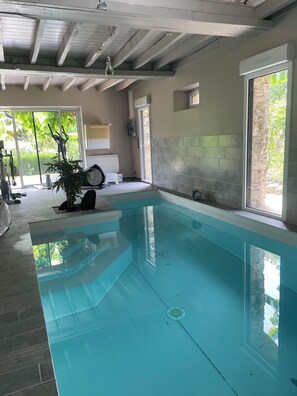 Piscina com vista desobstruída da área ao redor, incluindo uma porta, uma janela e uma planta.