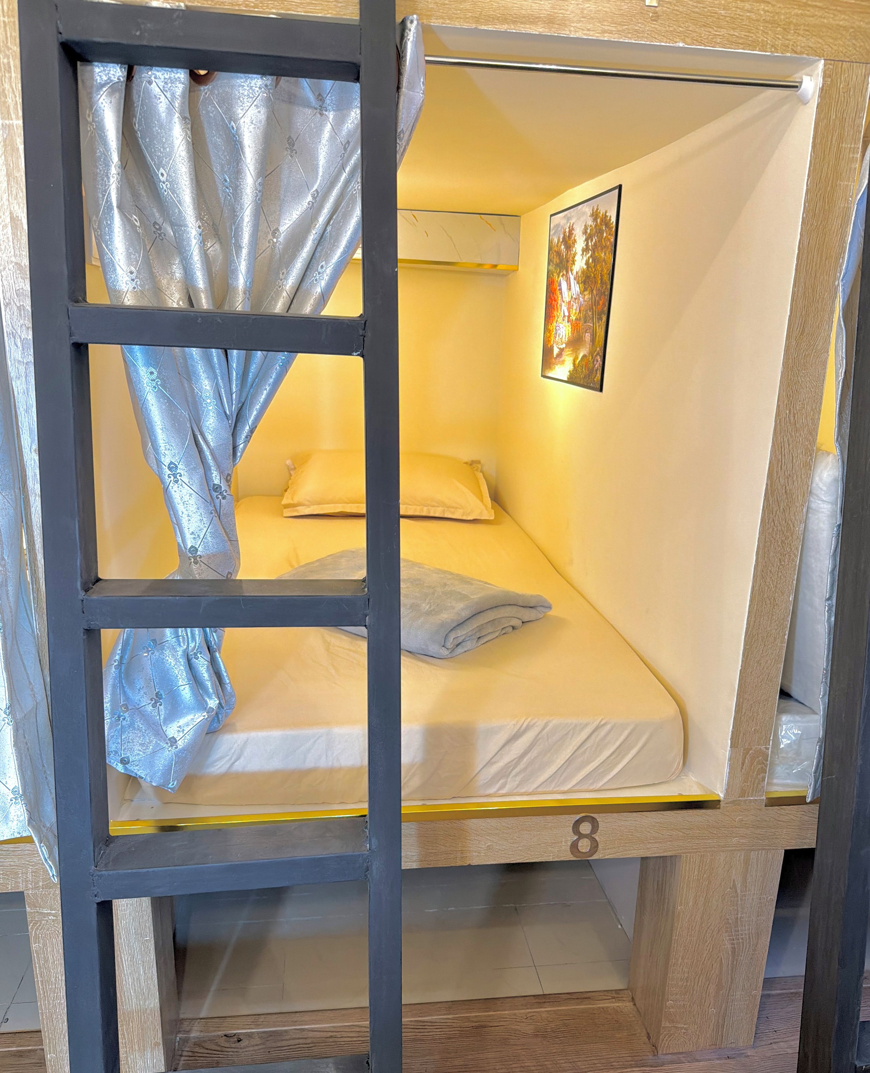 Uma cama de solteiro com cabeceira, cortina e um quadro na parede.