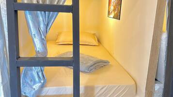 Uma cama de solteiro com cabeceira, cortina e um quadro na parede.