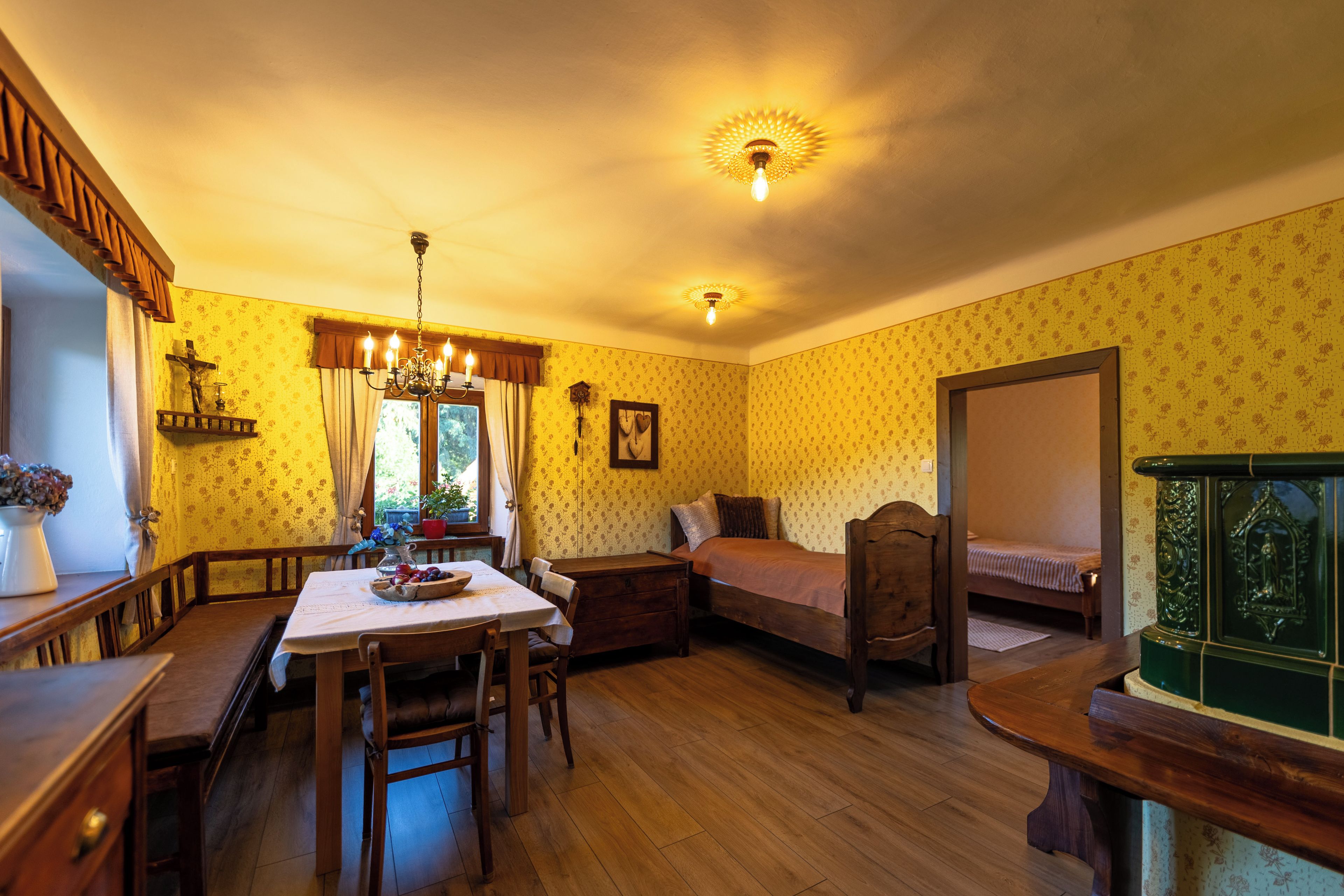 Quarto com mesa de jantar de madeira, uma cama, mesa de cabeceira e um armário verde.