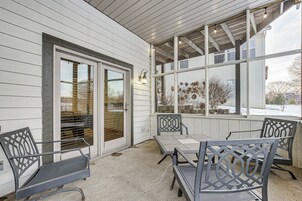 Um alpendre coberto com mesa e cadeiras, uma porta de vidro deslizante e vista para o exterior.