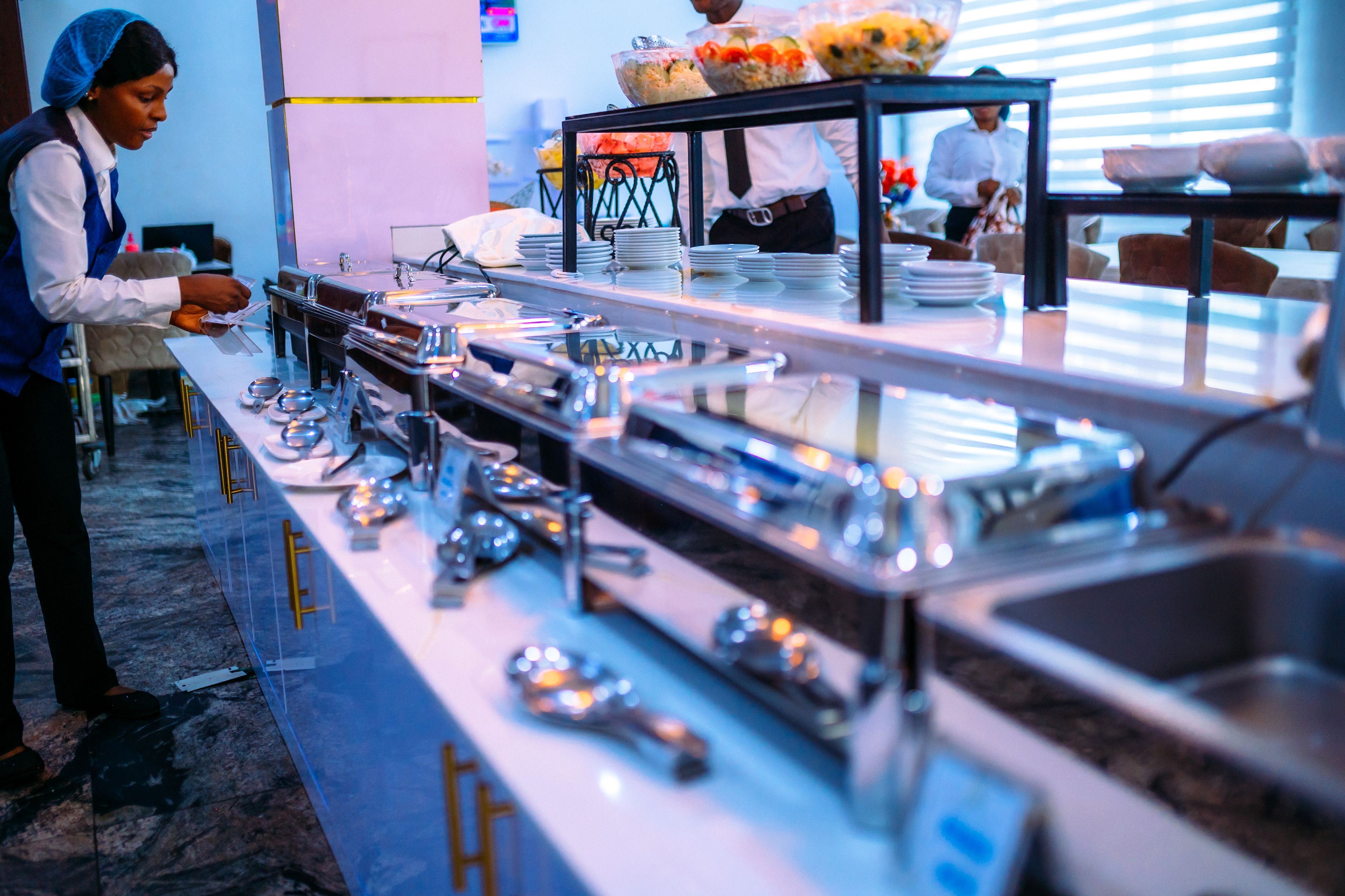 Uma mesa de buffet com várias estações de serviço, incluindo pratos, tigelas e talheres.