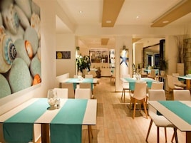 Um restaurante com várias mesas e cadeiras, uma ilha central e uma parede com padrão decorativo.