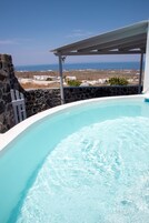 Piscina com vista para o mar e edifícios ao fundo.