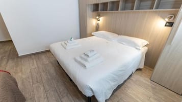 Quarto de hotel com cama, mesa de cabeceira, guarda-roupa e prateleira na parede.