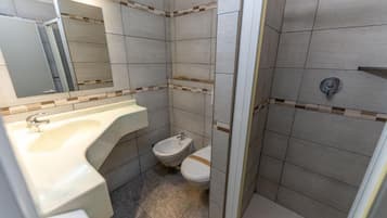 Casa de banho com lavatório, bidé, sanita e área de duche.