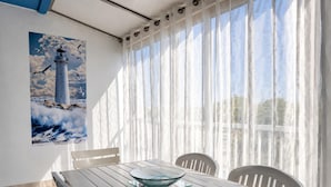 Uma área de refeições com mesa, cadeiras e uma pintura de um farol.