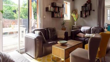 Uma sala de estar com sofá, poltronas, mesa de centro e estante de livros.