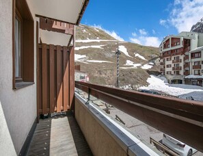 Varanda com vista para uma montanha coberta de neve e um edifício com varandas.